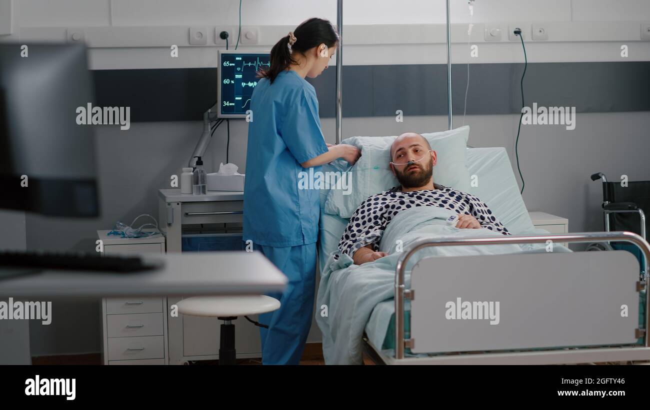 Practitioner asisstant arrange patient bed to sick man during sickness ...