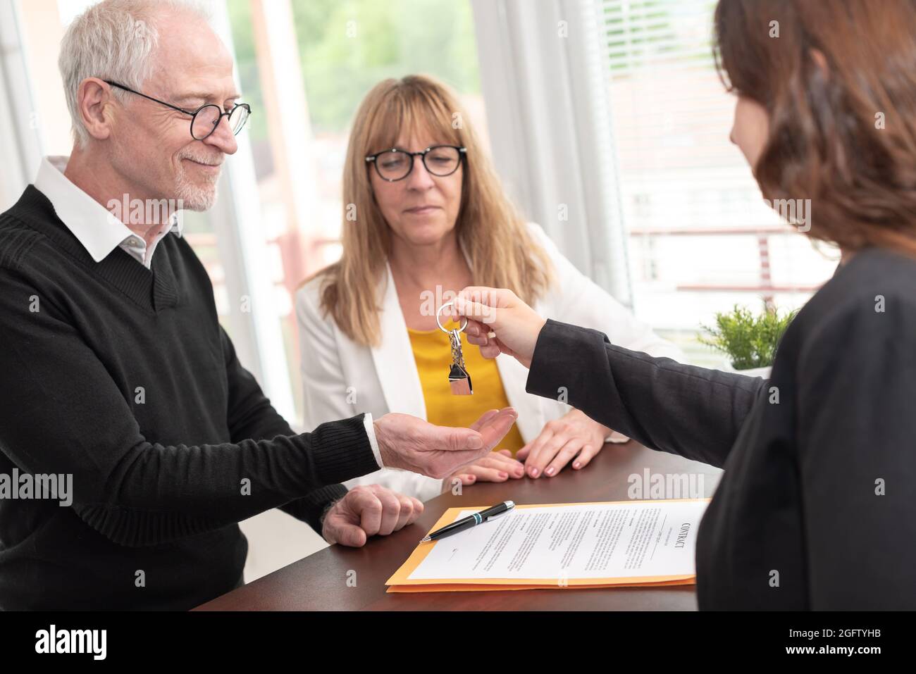 Happy senior couple getting house keys from female realtor Stock Photo ...