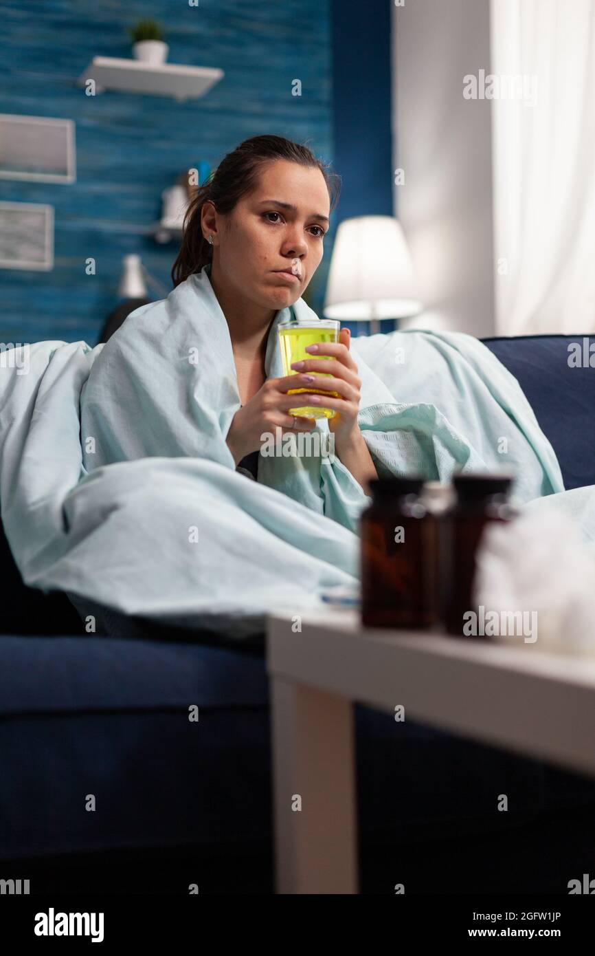 Caucasian woman sitting at home taking medicine for virus infection ...