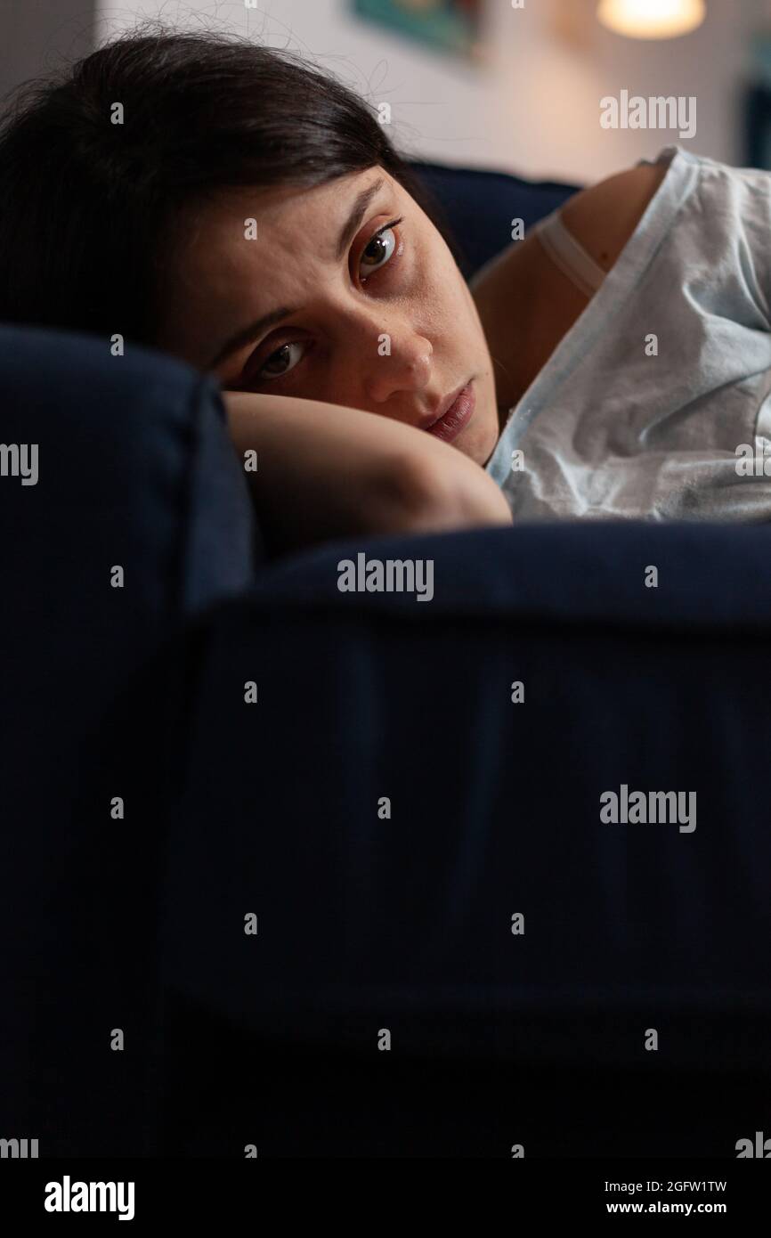 Traumatised depressed woman crying lying on sofa suffering from ...