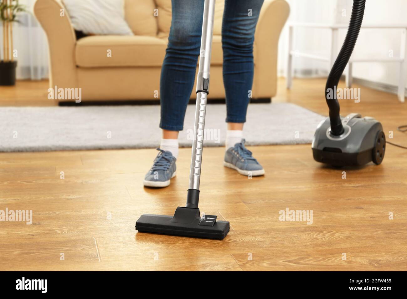 Cleaner hoovering floor in room Stock Photo - Alamy