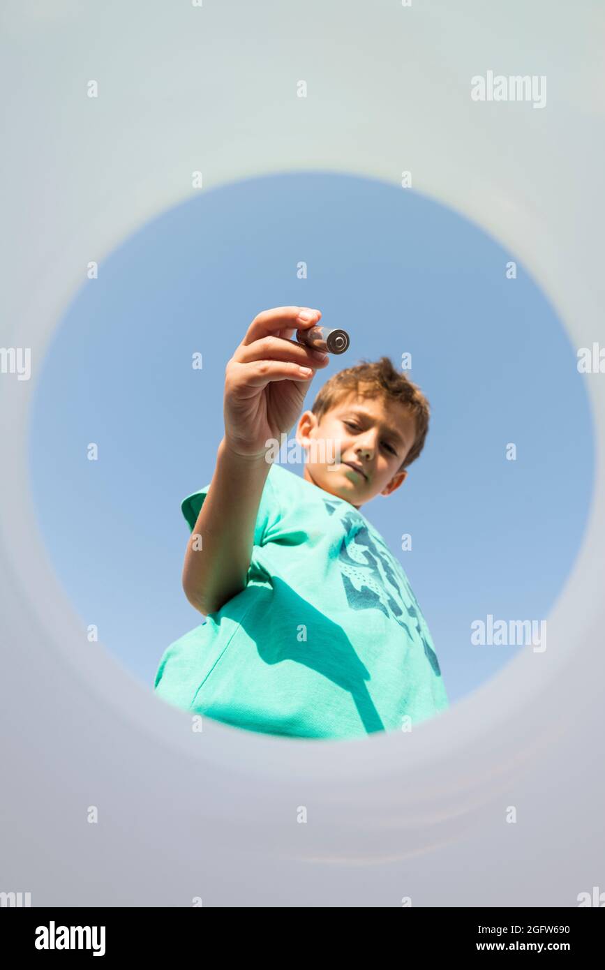 Child placing a pile inside a recycling bin, seen from inside the bin ...