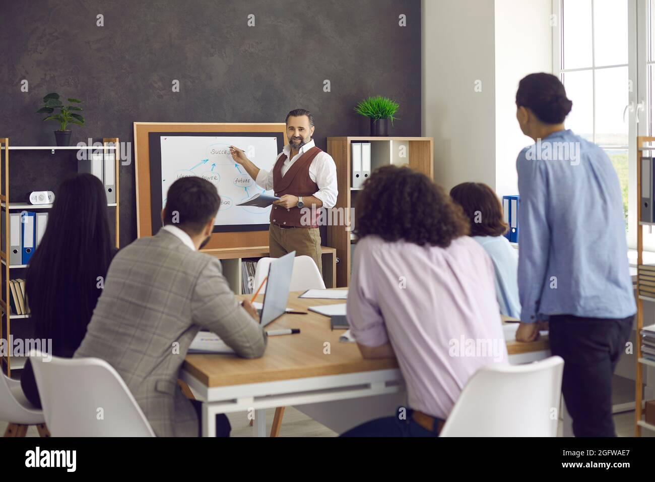 Male leader conducts a morning planning meeting in the office for his ...