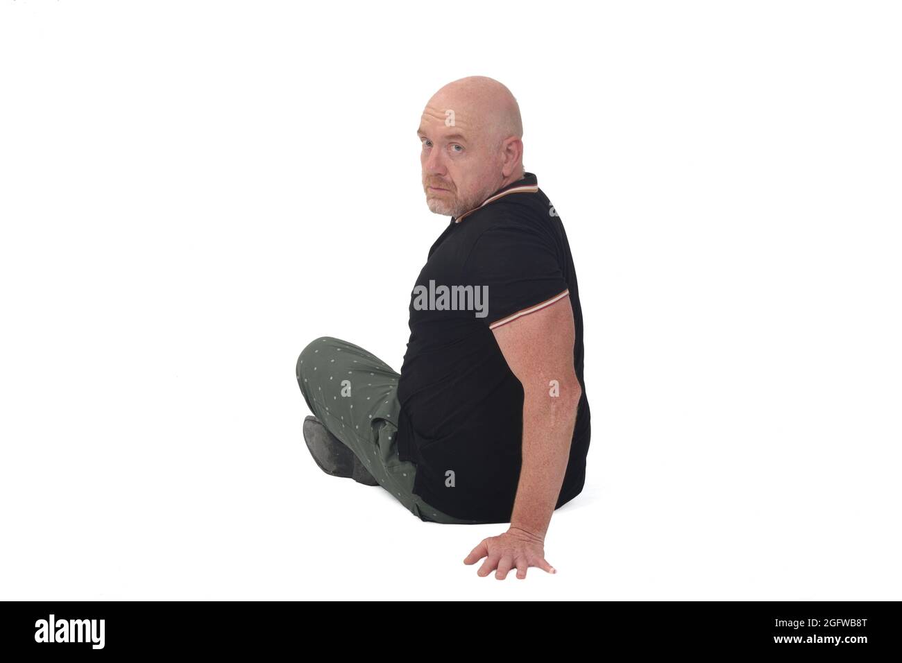 rear view of man sitting on floor looking at camera on white backgound ...