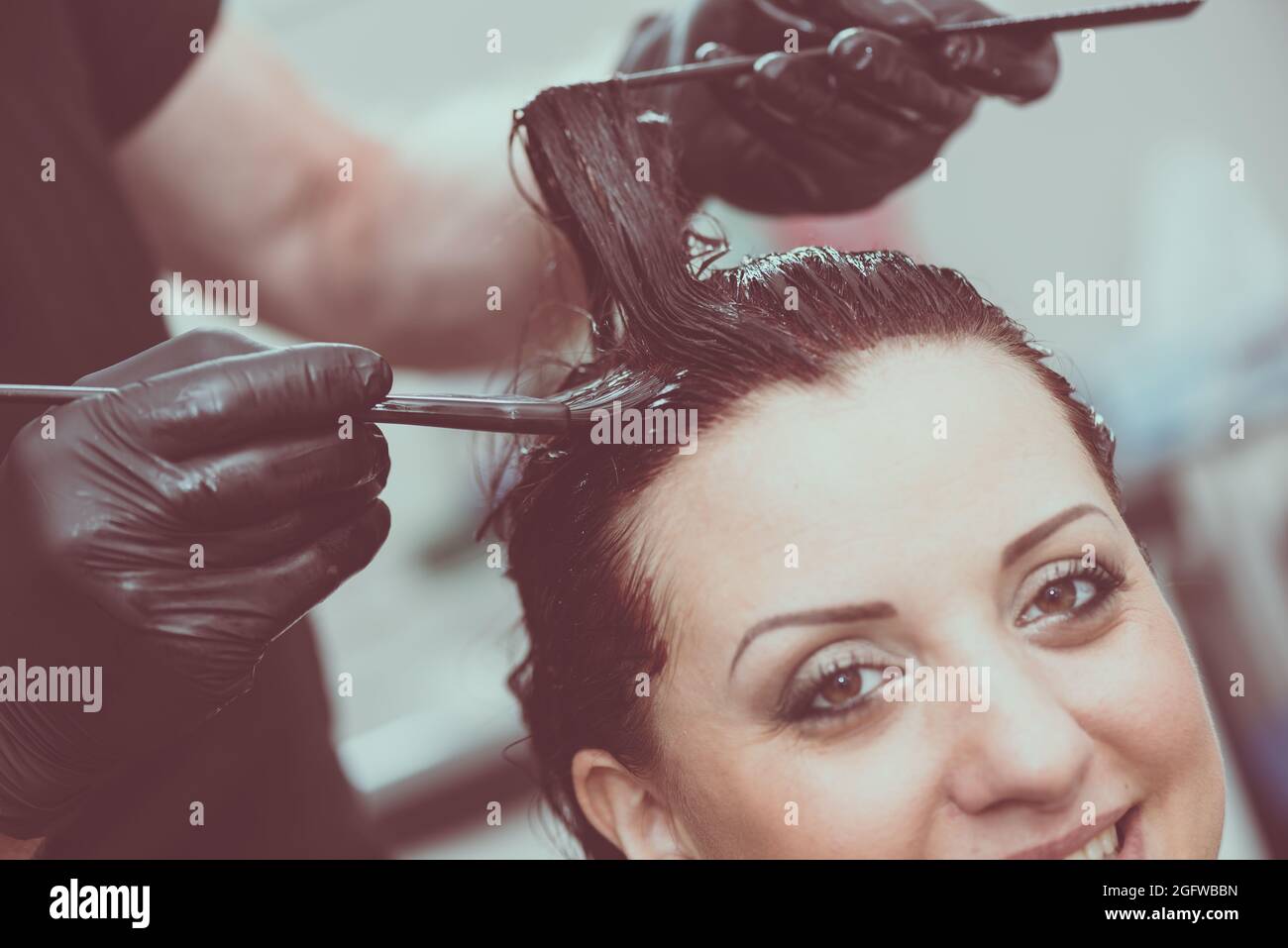 Hairdresser coloring client hair Stock Photo - Alamy