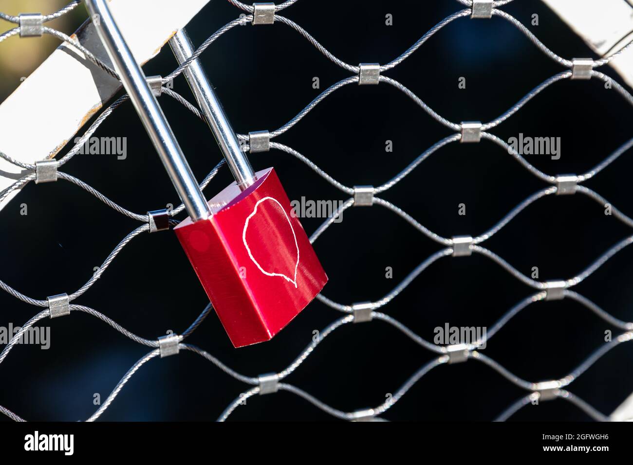Red lock with drawing heart locked on steel net cage with dark inside ...