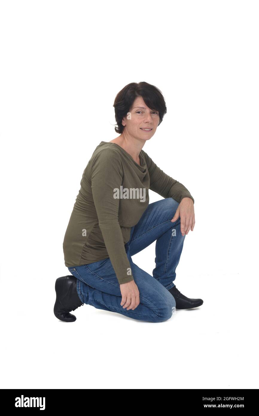 side view of crouching woman and looking at camera on white background ...
