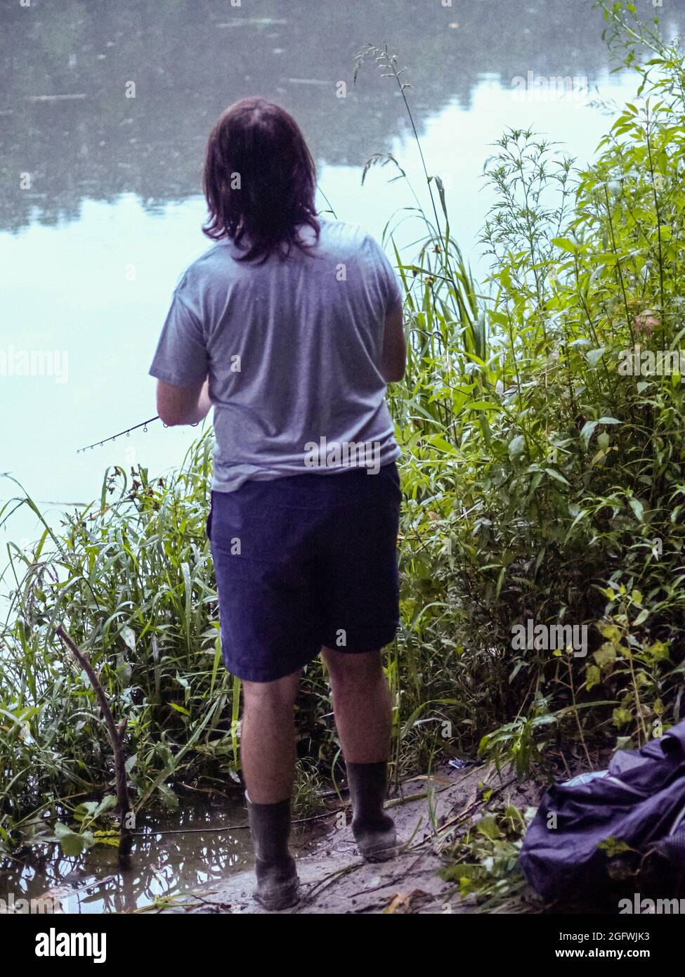 Rear view of man fishing by the river Stock Photo - Alamy