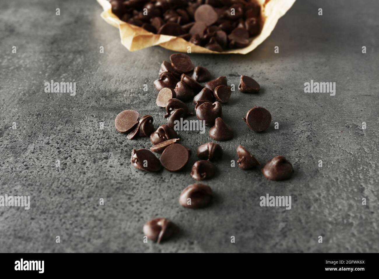 Tasty chocolate chips and parchment on dark textured background Stock ...