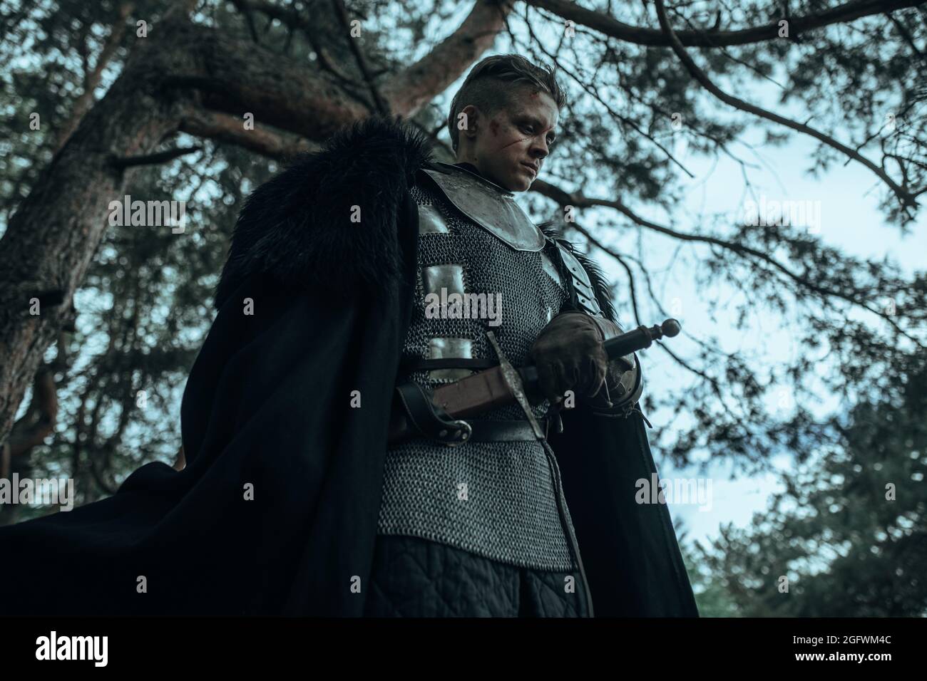 Medieval warrior knight in chain mail armour and black cape stands ...