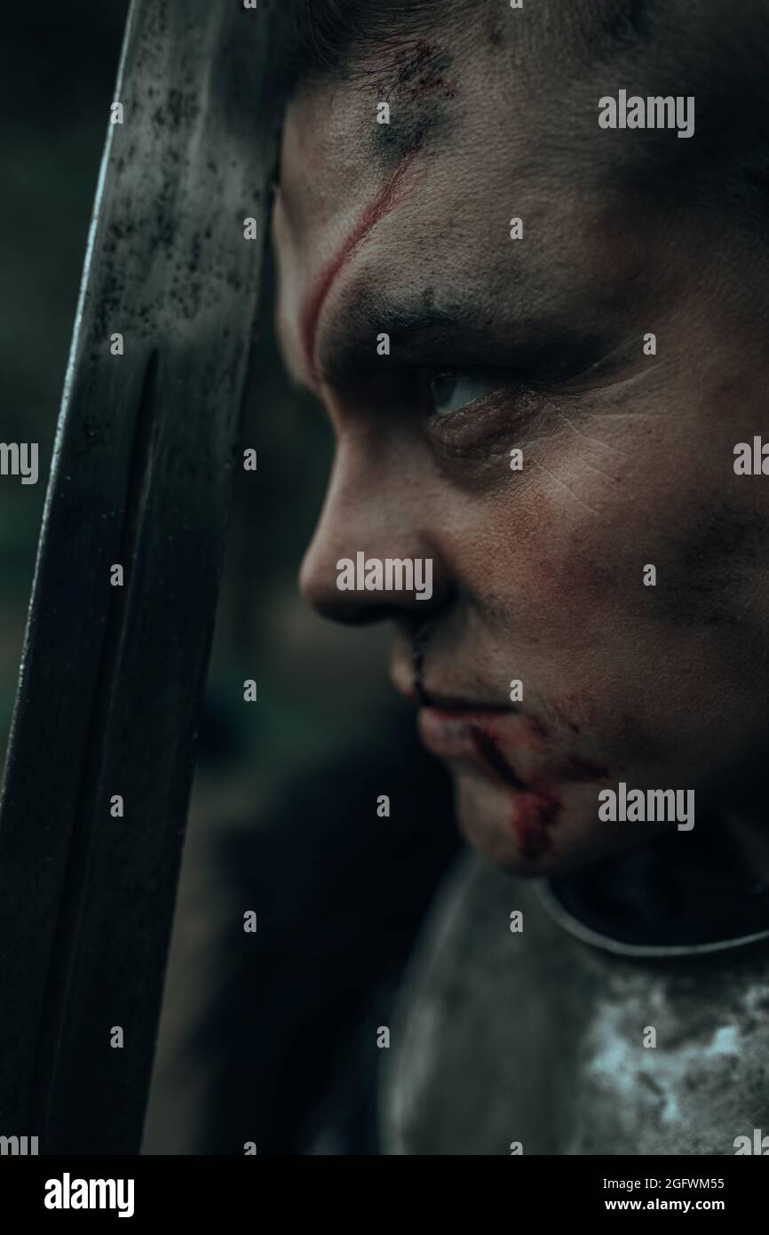 Portrait of medieval warrior knight with bloody face and scar in armour ...