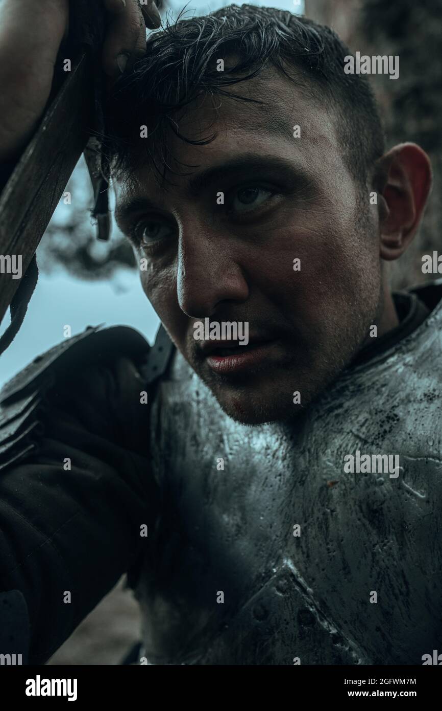 Medieval tired warrior knight in chain mail armour sits and rests among ...