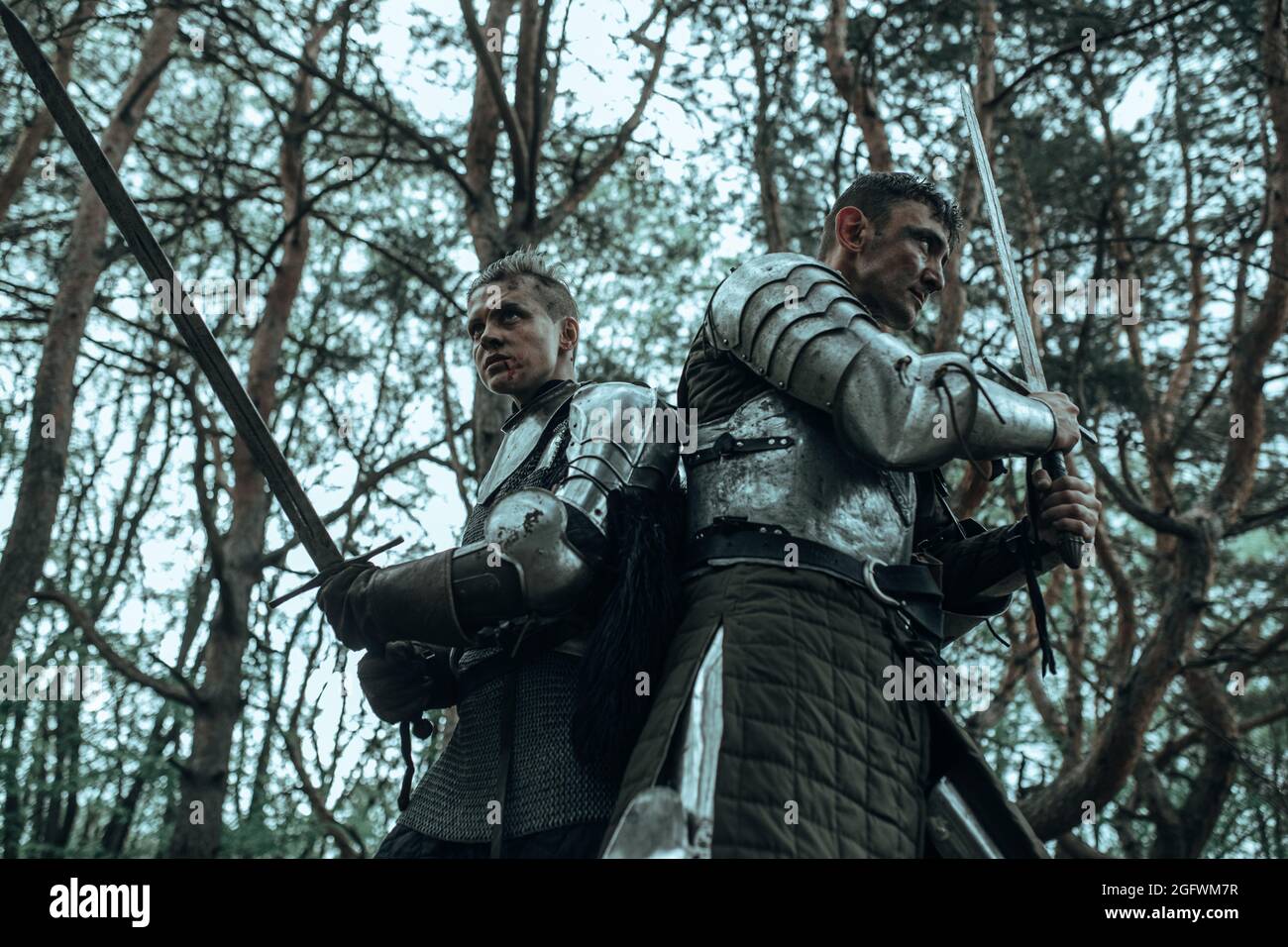 Two medieval warriors knights in chain mail armour stand back to back ...