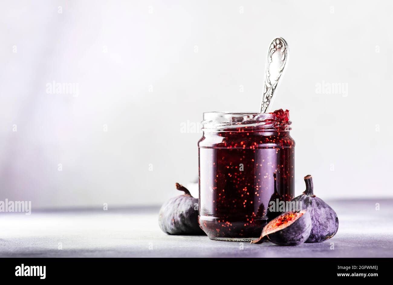 Fig confiture in glass jar. Fresh fruits on gray kitchen table ...