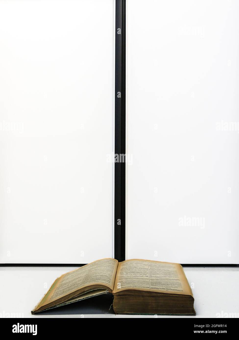 Ancient open book with the white wall in the background Stock Photo - Alamy