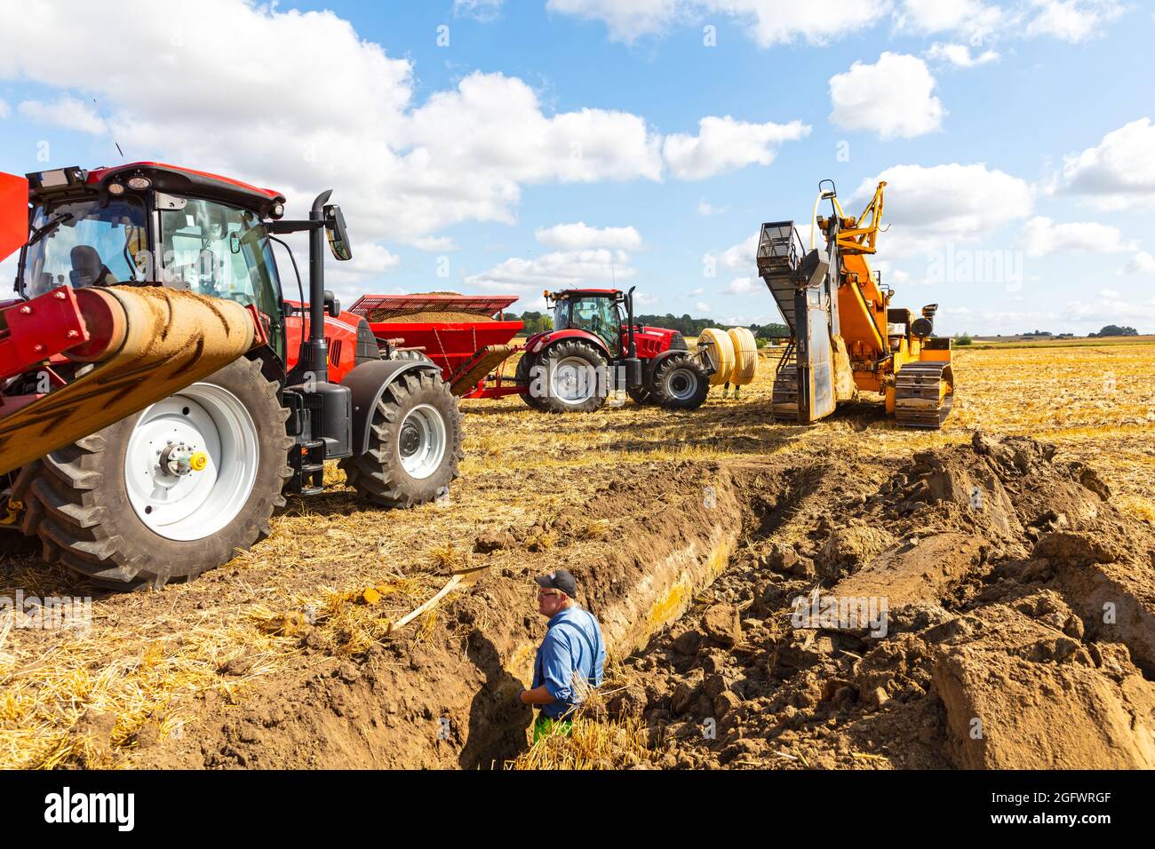 Tractors in field and man standing in ditch Stock Photo - Alamy