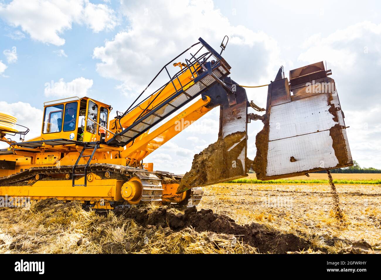 Machine digging ditch in field Stock Photo - Alamy