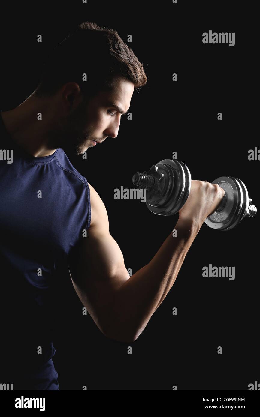 Sporty man doing exercises with dumbbell on black background Stock ...