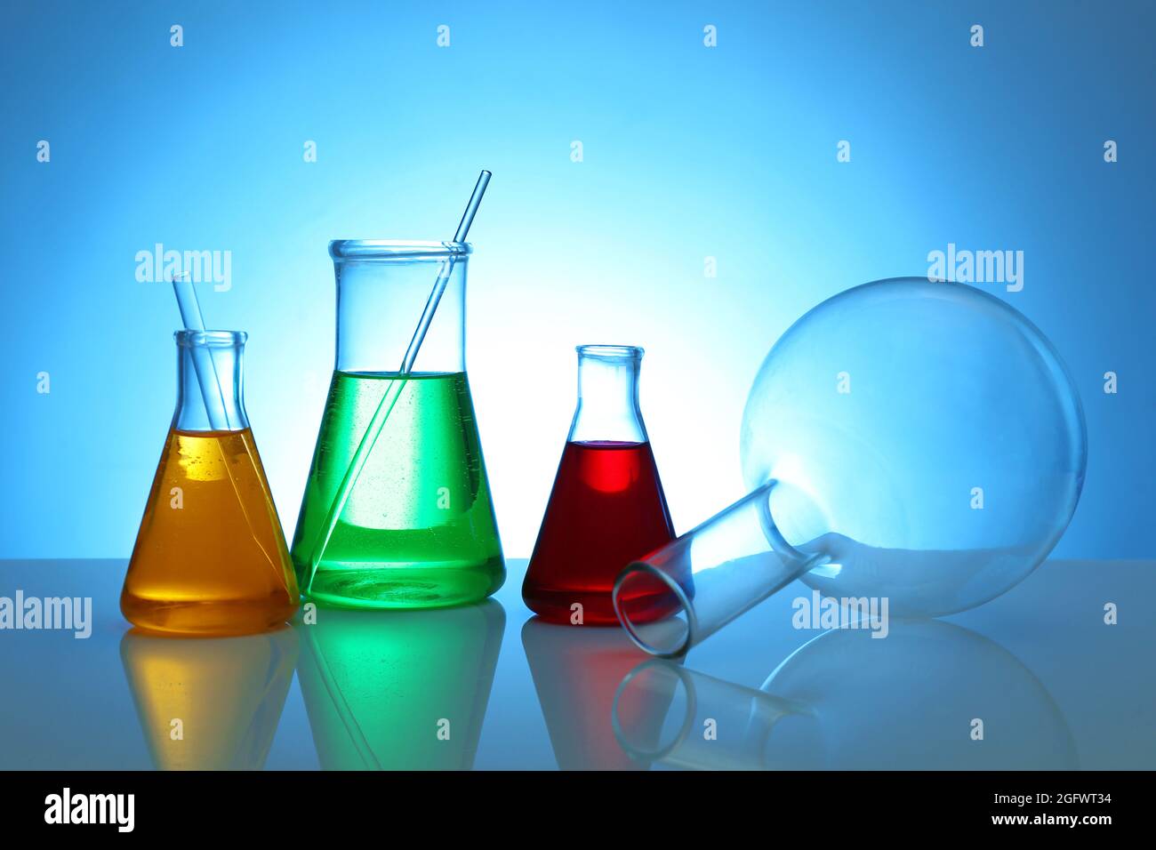 Test beakers and flasks on color background Stock Photo - Alamy