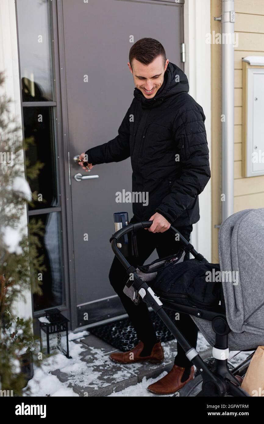 Smiling man entering house with pram Stock Photo - Alamy