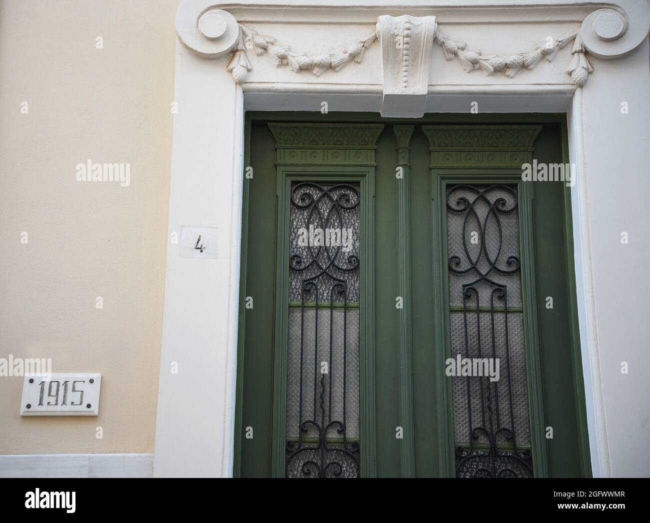 Neoclassical house facade with an olive green wooden entrance door ...