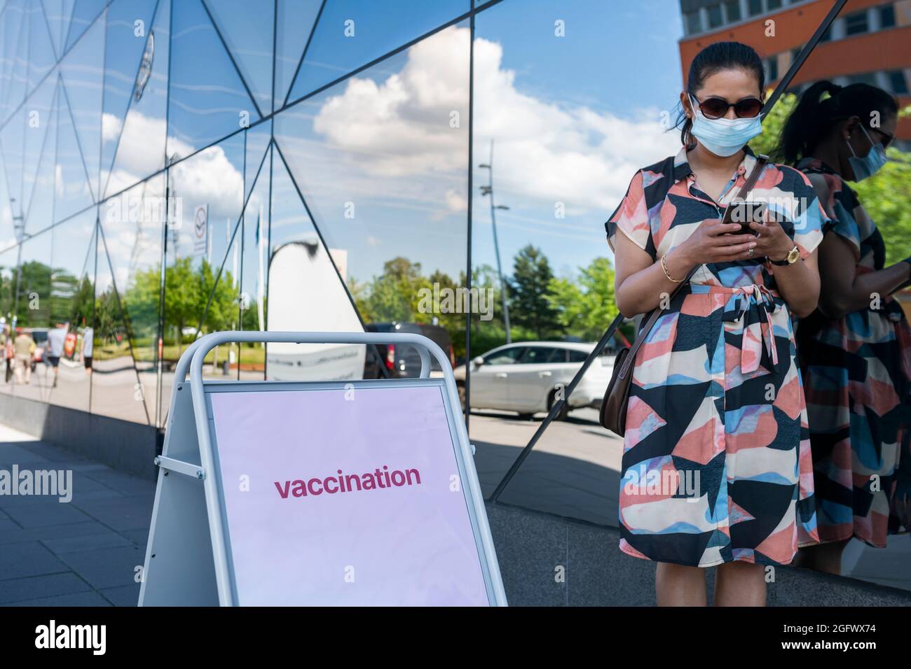 Woman standing next to covid-19 vaccination sign Stock Photo - Alamy