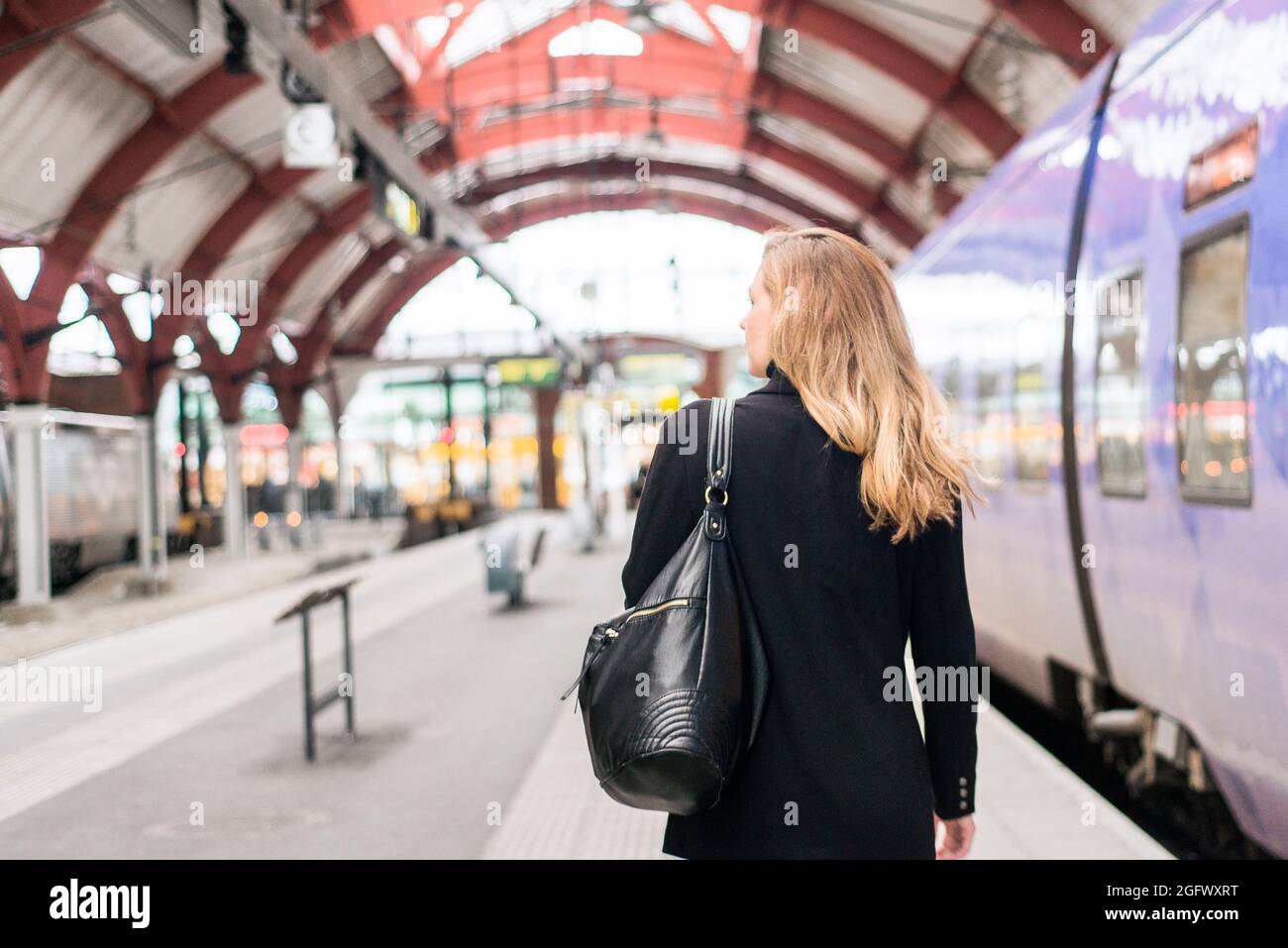 Woman looking around at train station Stock Photo - Alamy