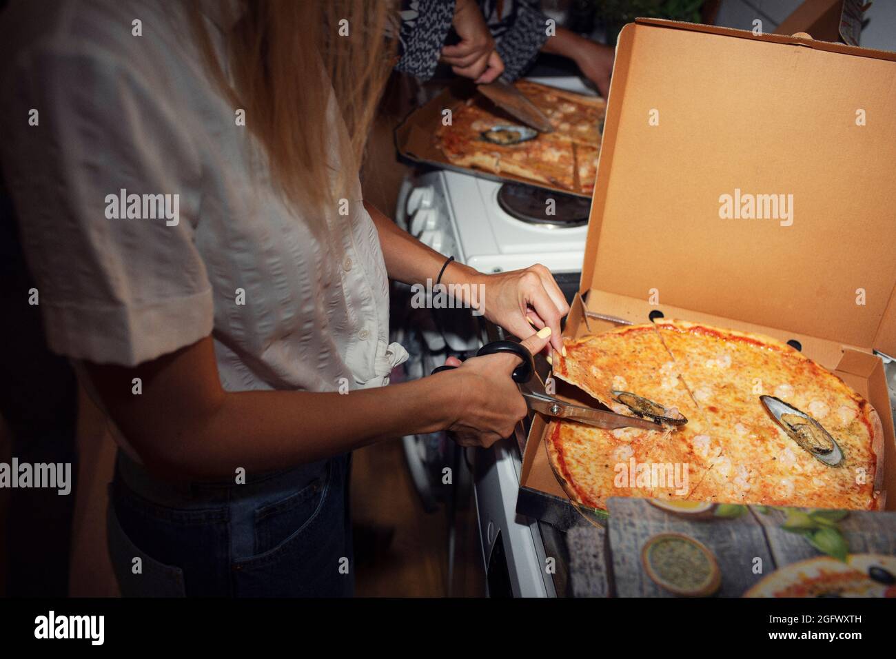 Woman cutting pizza with scissors Stock Photo - Alamy