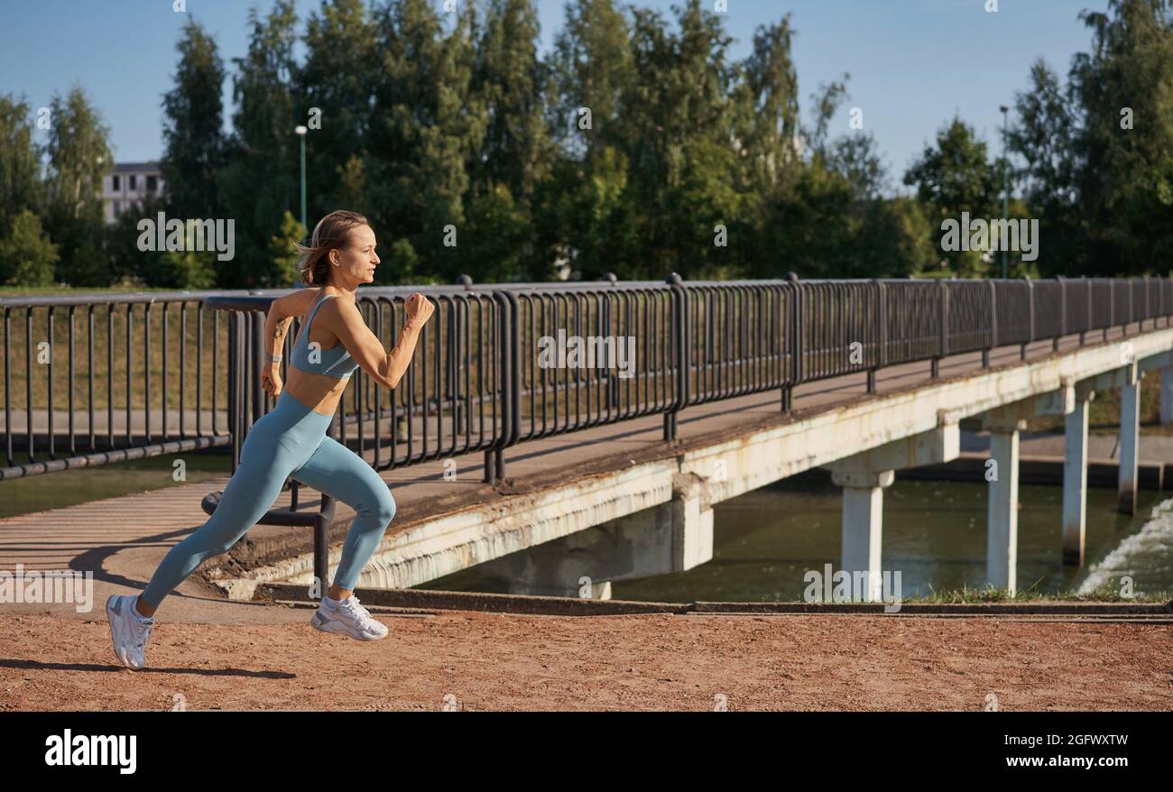Beautiful female jogger running in the morning across bridge Stock ...