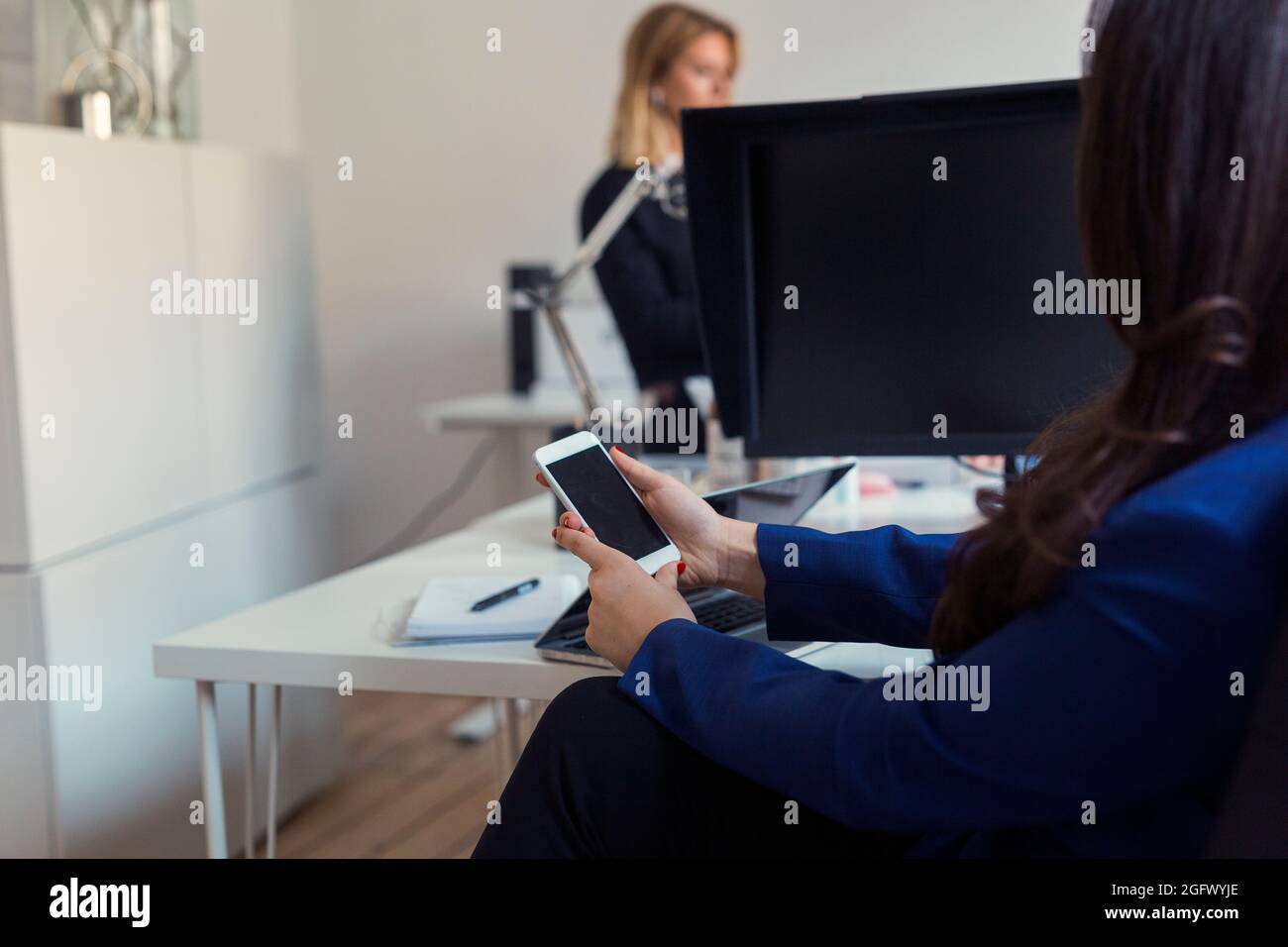 Woman in office using cell phone Stock Photo - Alamy