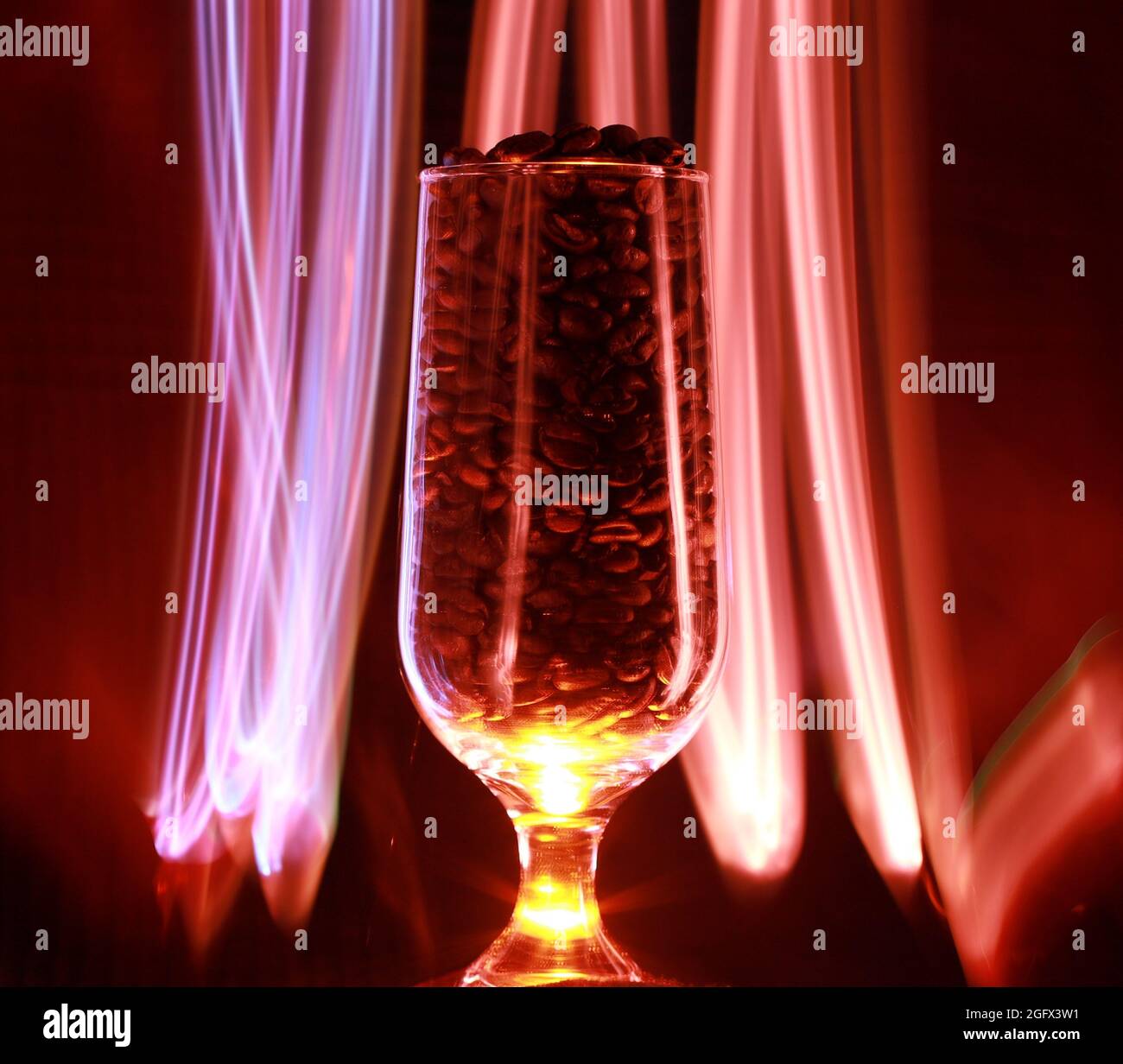 Long exposure shot of coffee beans in a transparent cup with led lights ...