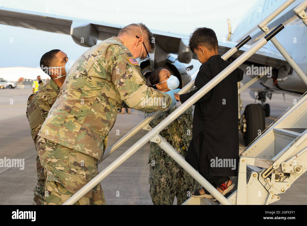 Sigonella, Italy. 26th Aug, 2021. U.S. service members assist an Afghan ...