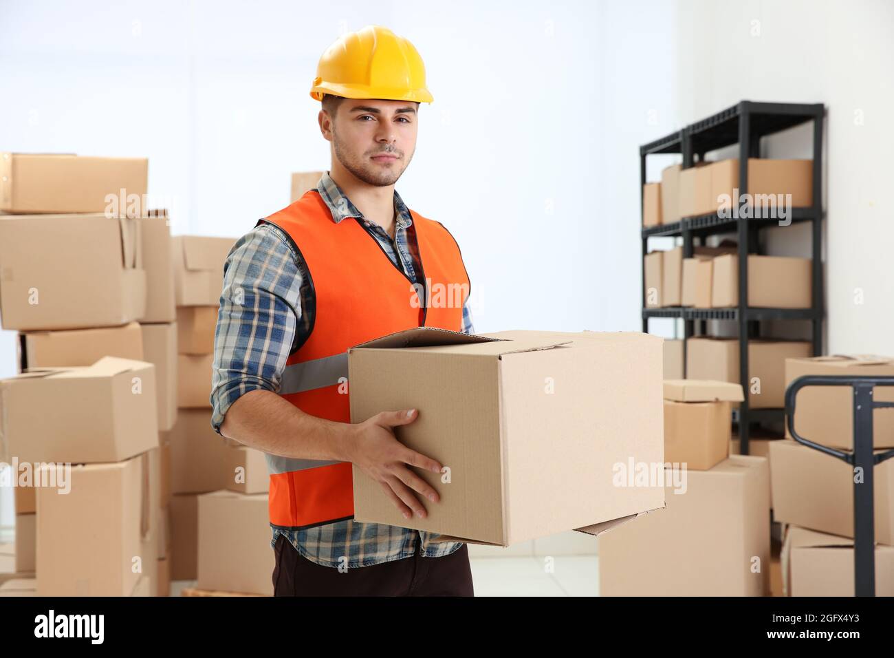 Handsome worker holding cartoon box at warehouse Stock Photo - Alamy