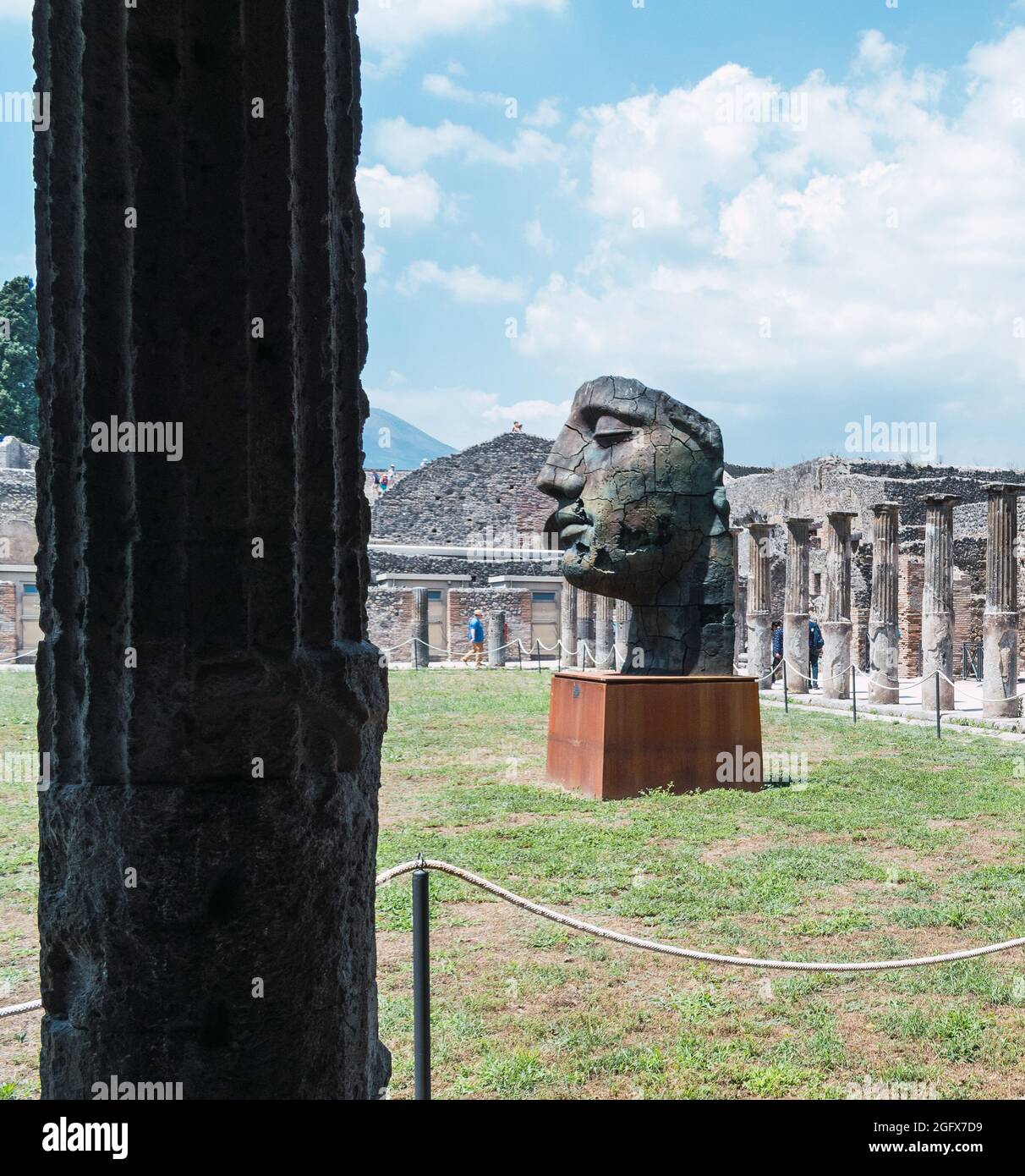 Vertical shot of damaged bust by ancient bricks in ruins of pompeii ...