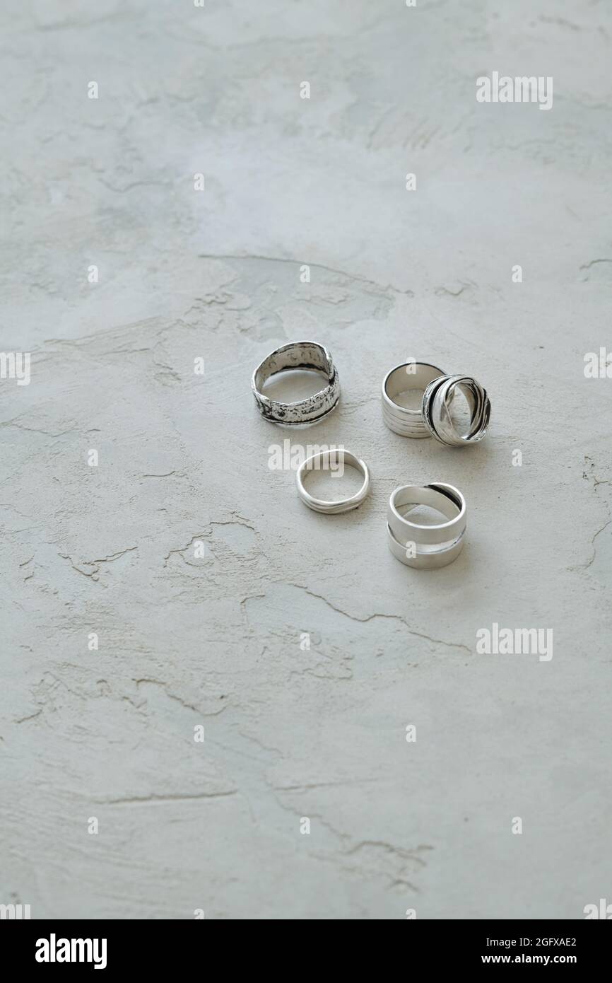 Various handmade silver rings placed on plaster textured surface ...