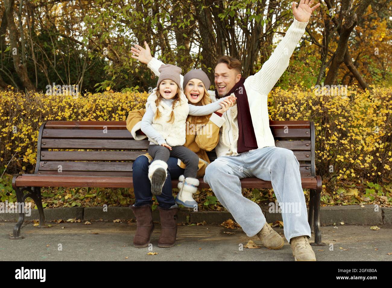 Happy family sitting on bench in beautiful autumn park Stock Photo - Alamy