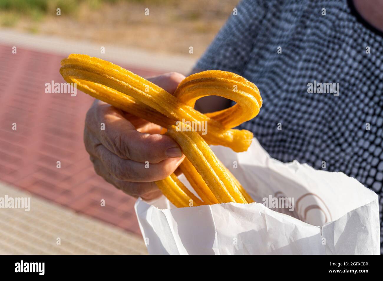 Close-up shot of an old woman holding the delicious deep-fried Spanish ...