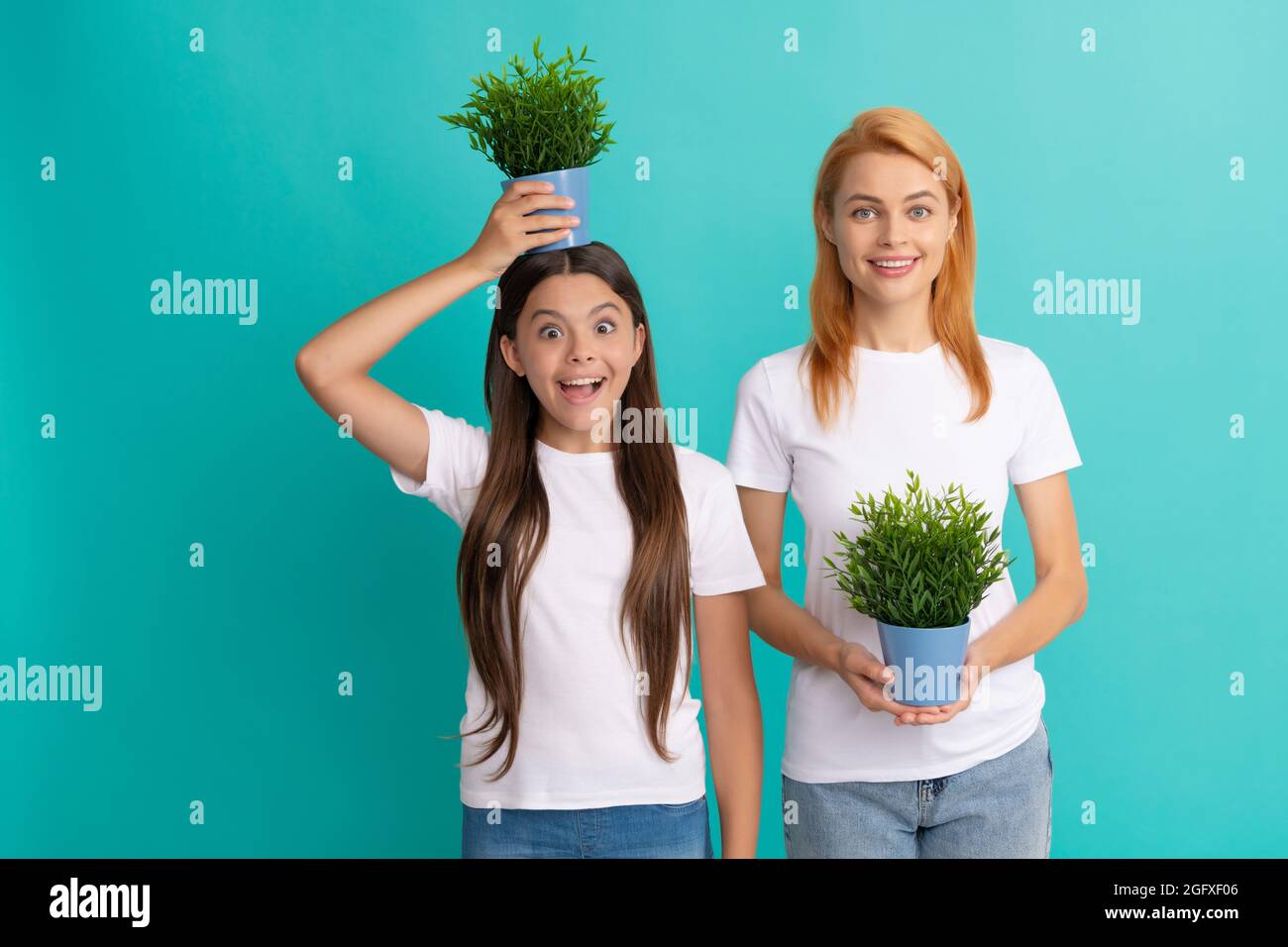 Family of mother and surprised girl child holding pot plant on head to ...