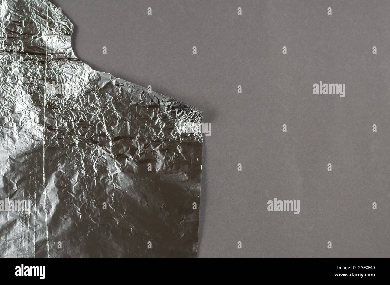 Crumpled foil against a gray background. Roll of aluminum foil for food ...