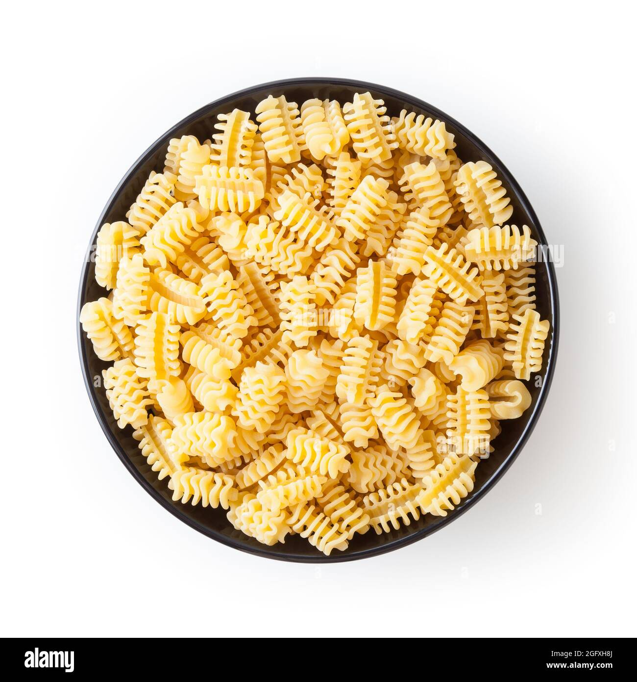 Uncooked radiatori pasta in black bowl isolated on white background ...