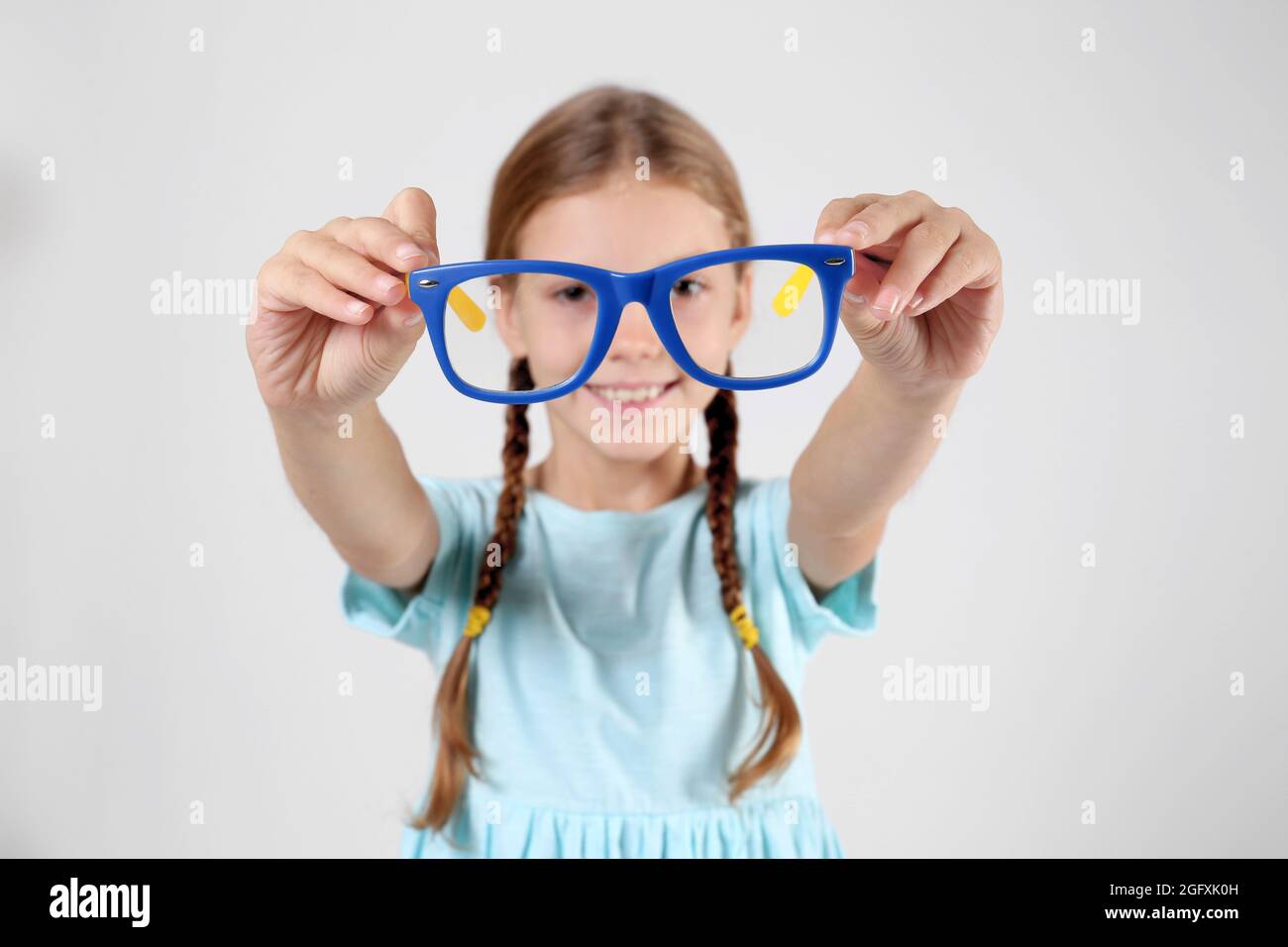 Little girl with spectacles on light background Stock Photo - Alamy