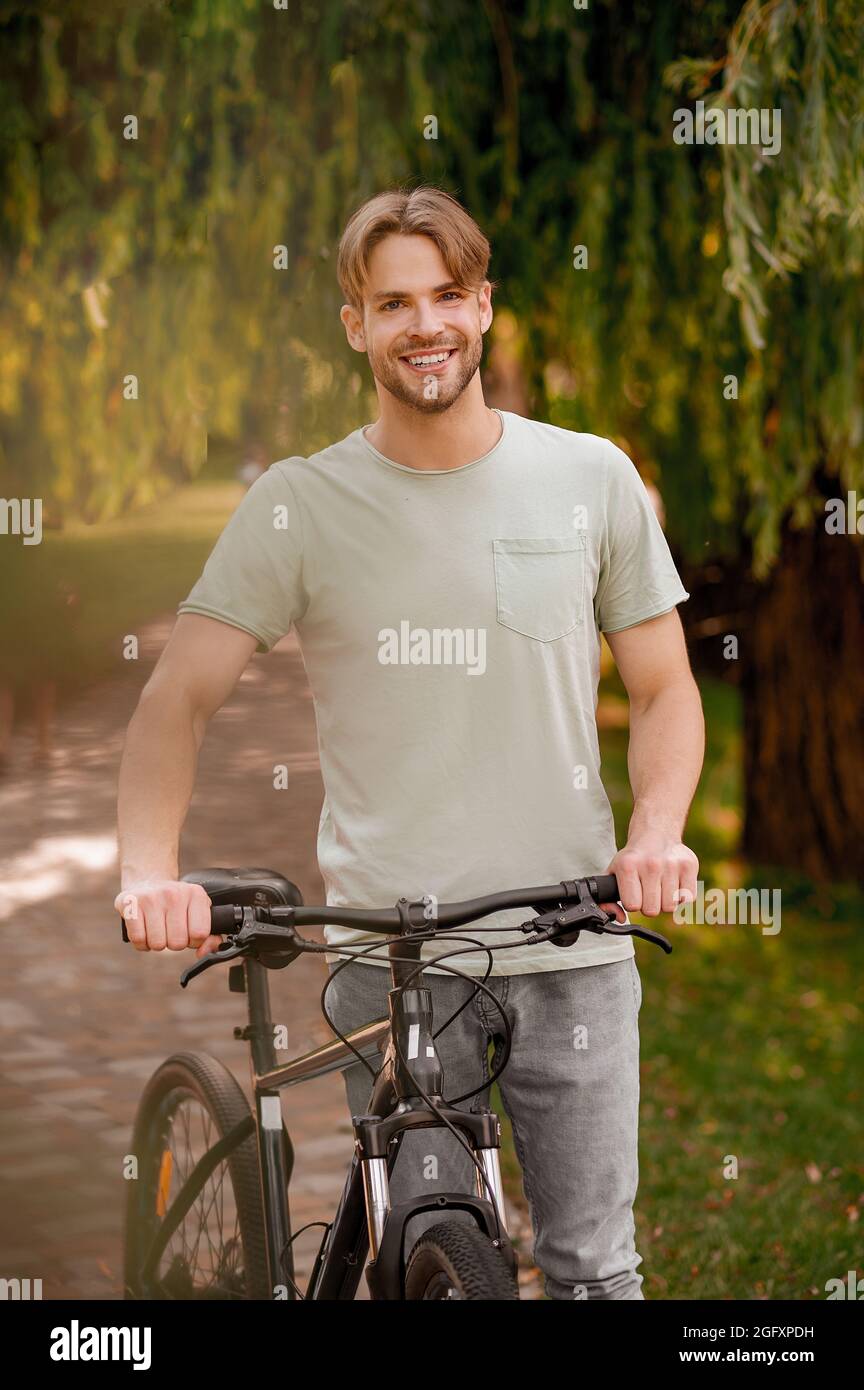 Joyful male bike rider standing in a park Stock Photo - Alamy