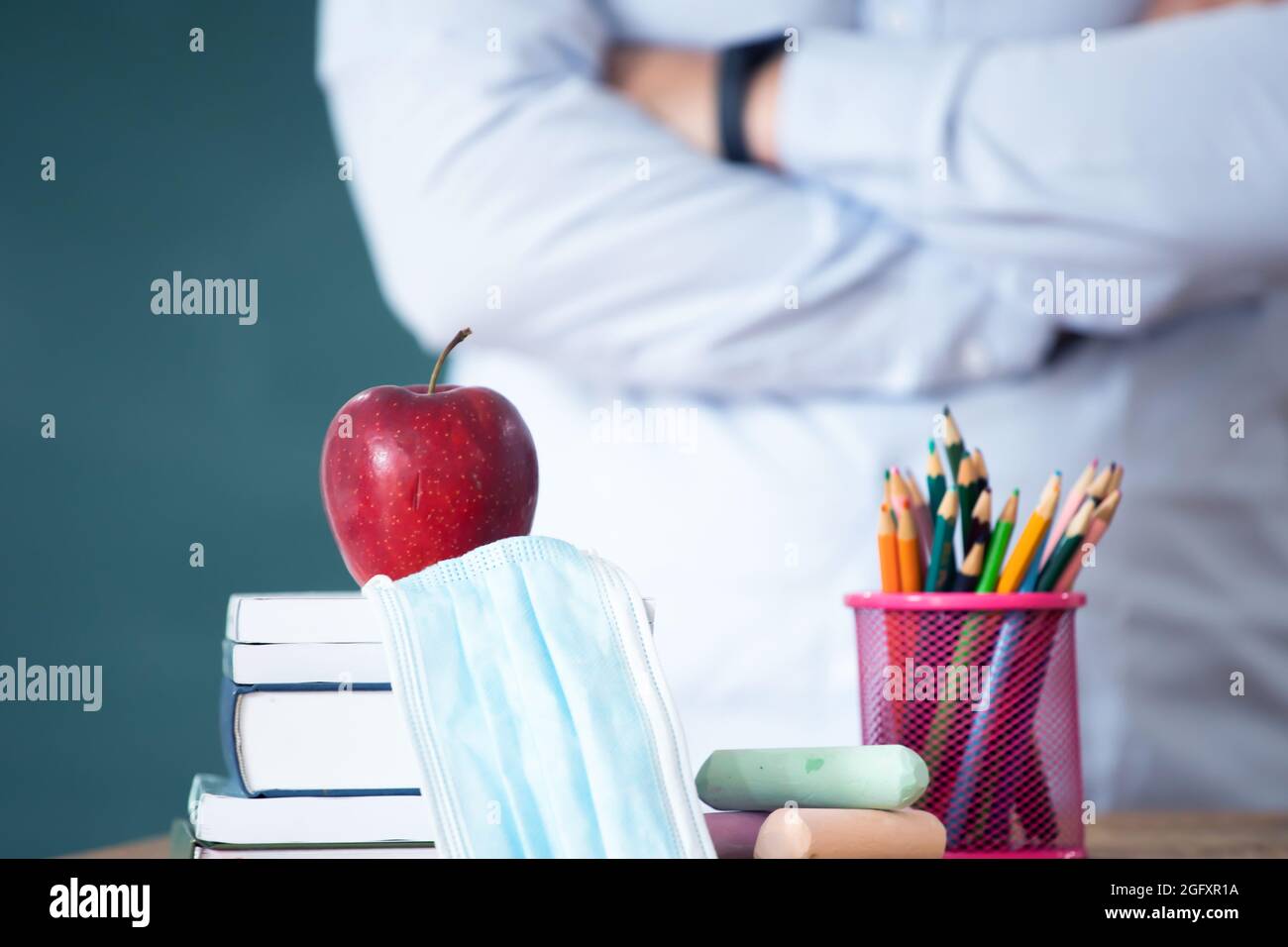Teacher holding face mask welcoming children back at school after ...