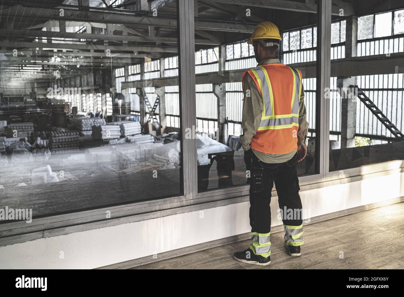 Closeup of the worker standing in front of the windows and looking ...
