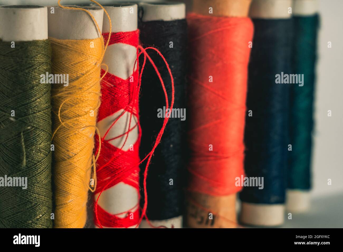 Selective focus shot of colorful thread on round stocks piled in row ...