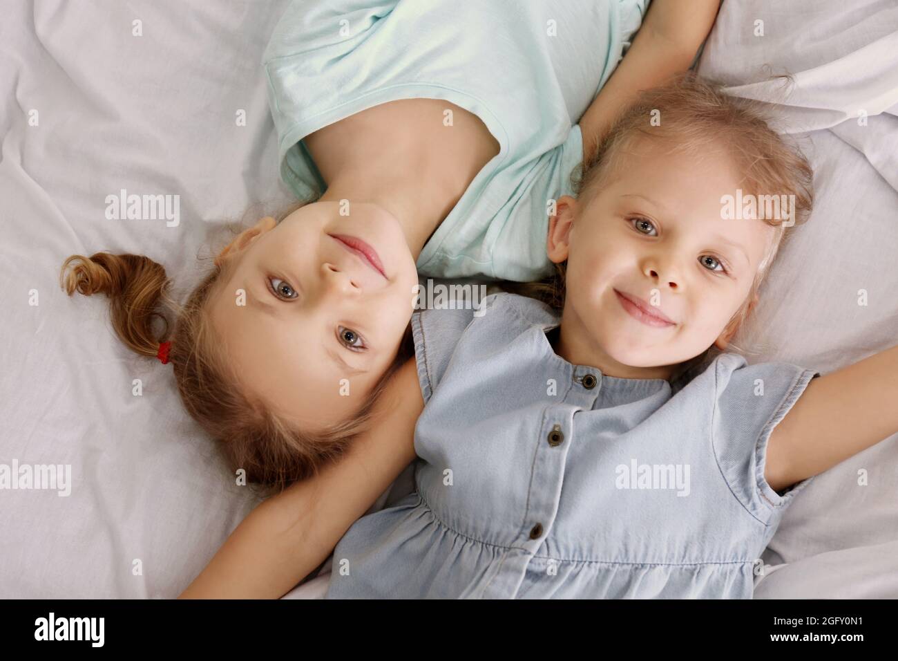Adorable little sisters lying in bed, top view Stock Photo - Alamy