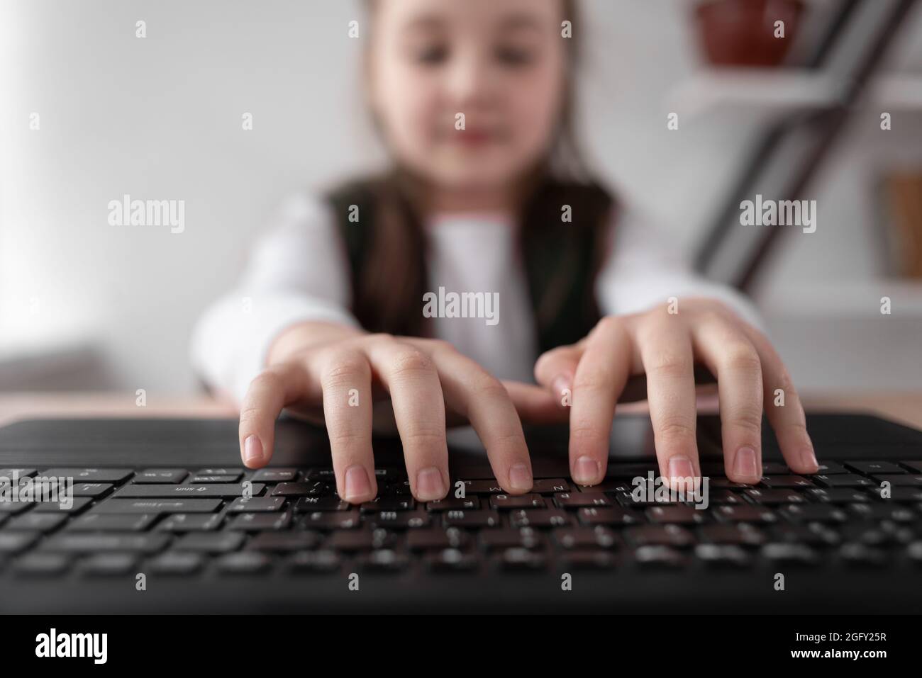 Close-up of kid's hands are typing text on the keyboard. Webcam view ...