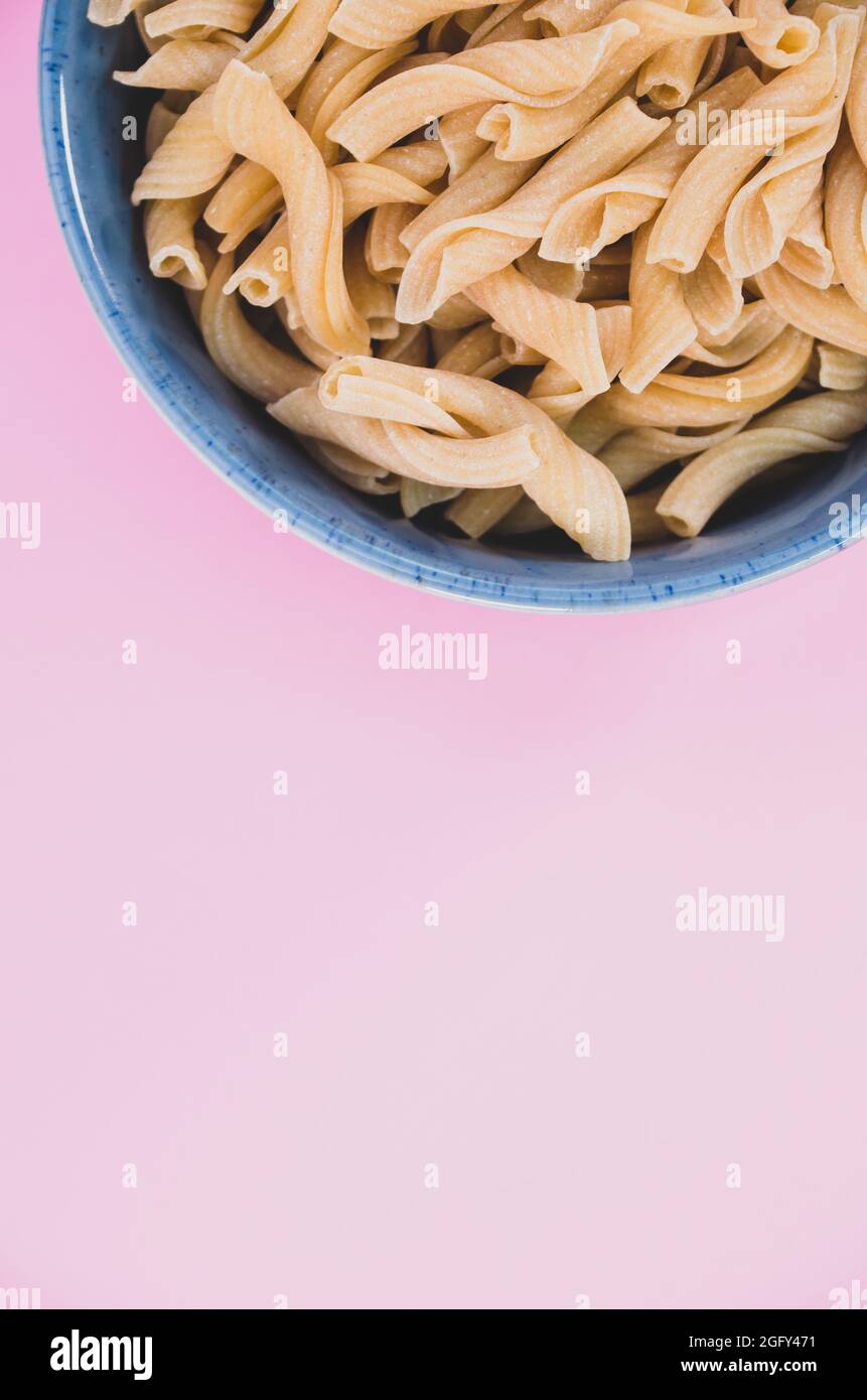 Bowl of cooked pasta on the top of a soft pink background with copy ...