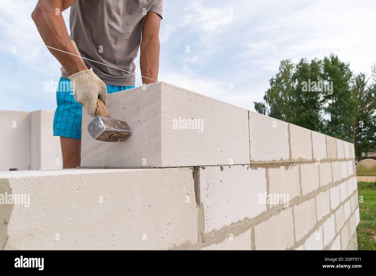 Builder uses a hammer to tamp aerated concrete blocks on the ...
