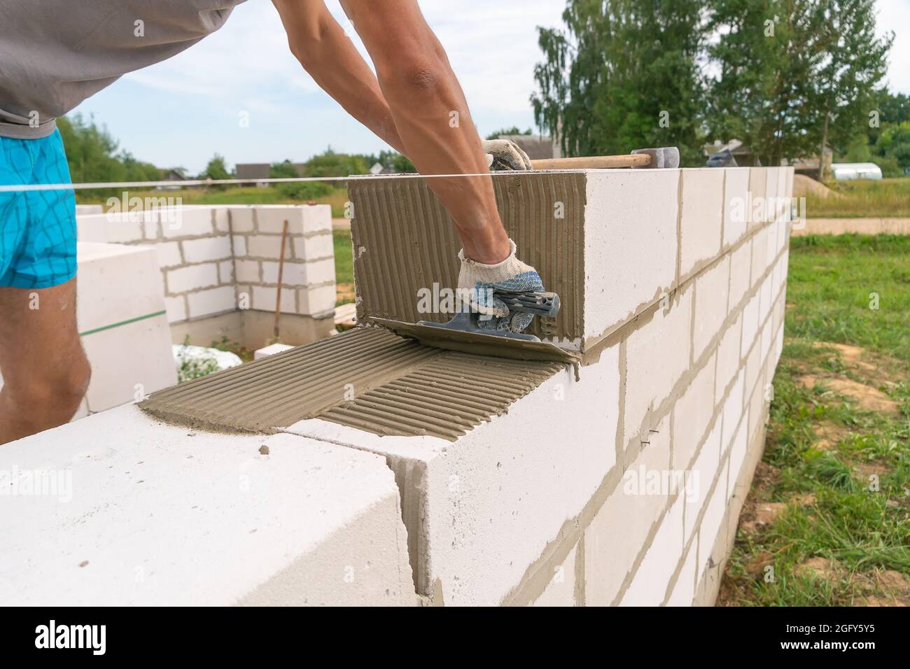 Builder uses a notched trowel to apply the cement mixture to the ...